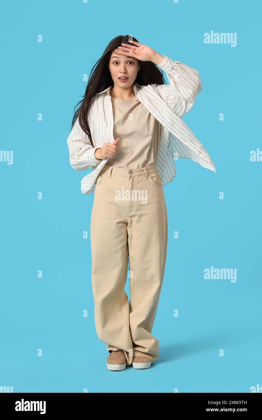 Shocked young Asian woman with strong wind on blue background Stock ...