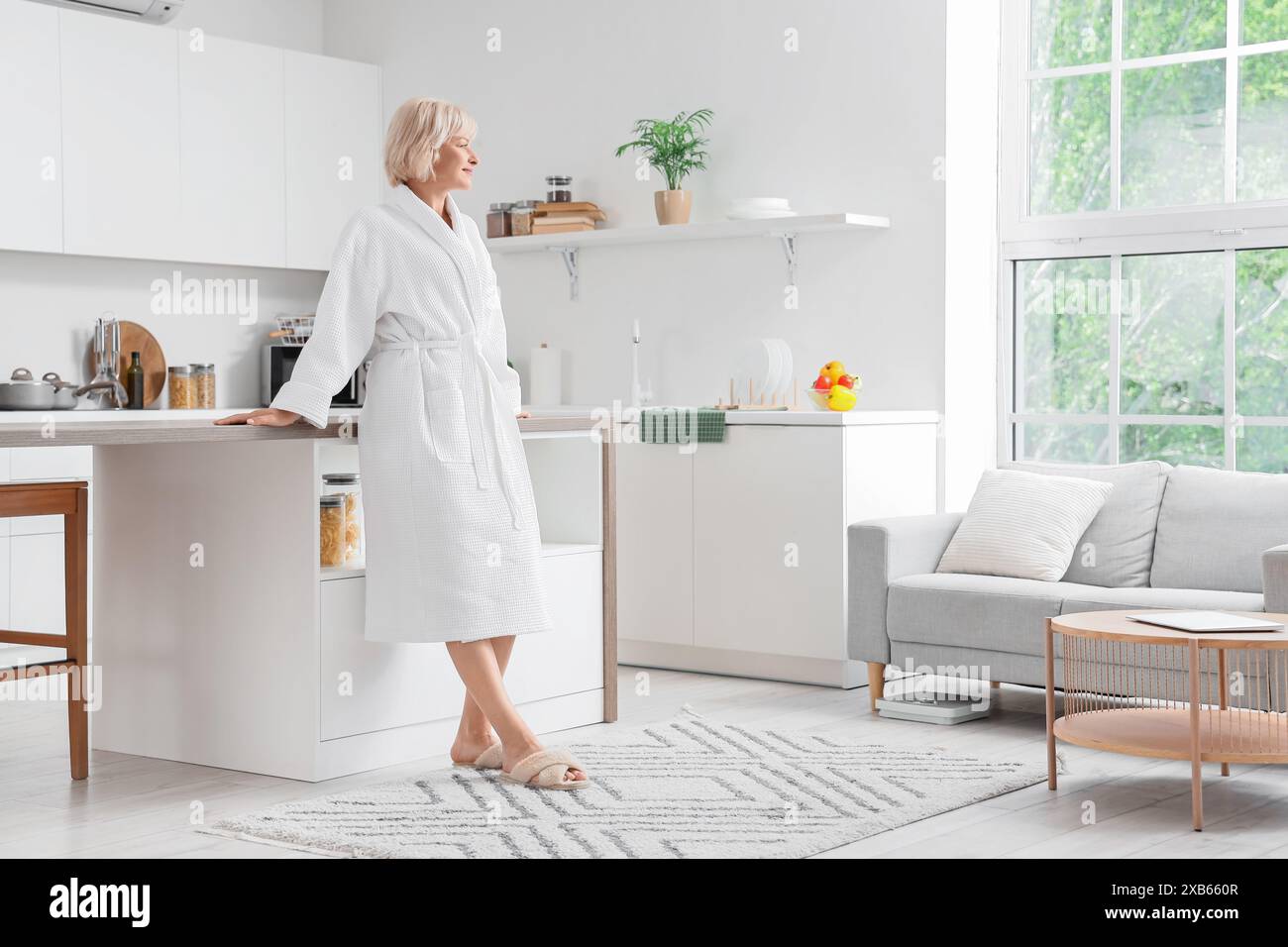 Middle-aged woman in bathrobe at kitchen Stock Photo - Alamy