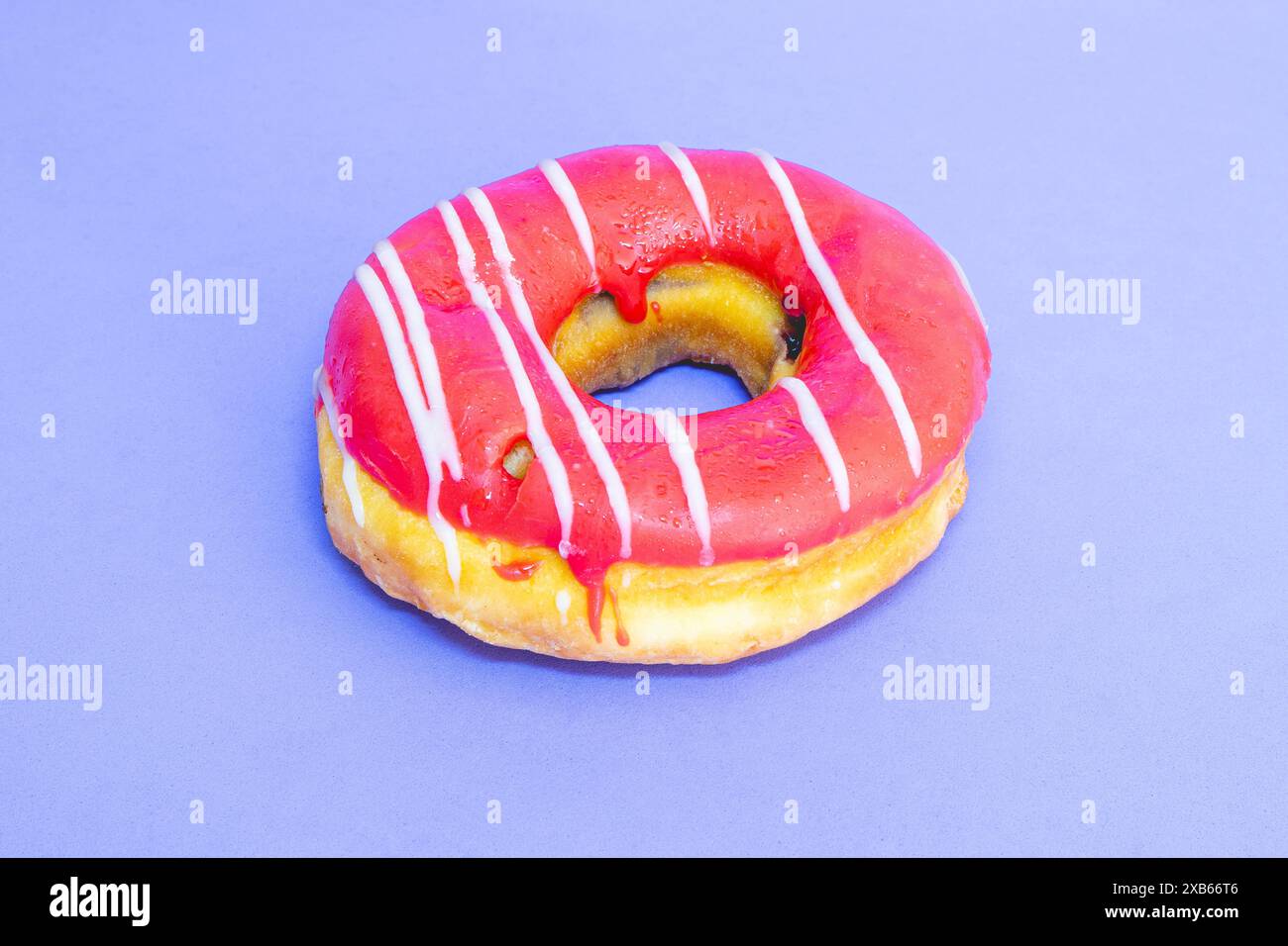 Single donut with topping laying on a blue background Stock Photo - Alamy