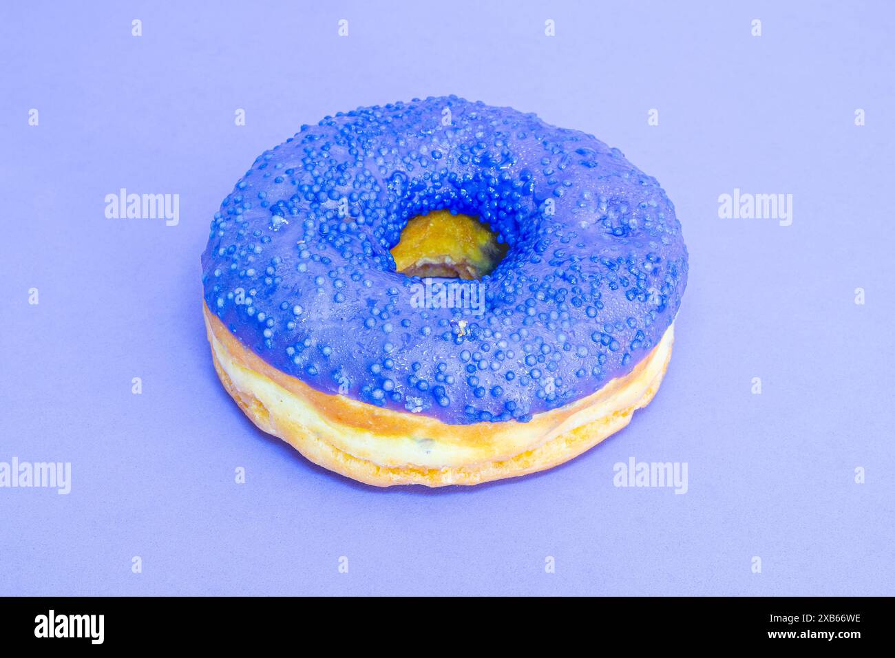 Single donut with topping laying on a blue background Stock Photo - Alamy