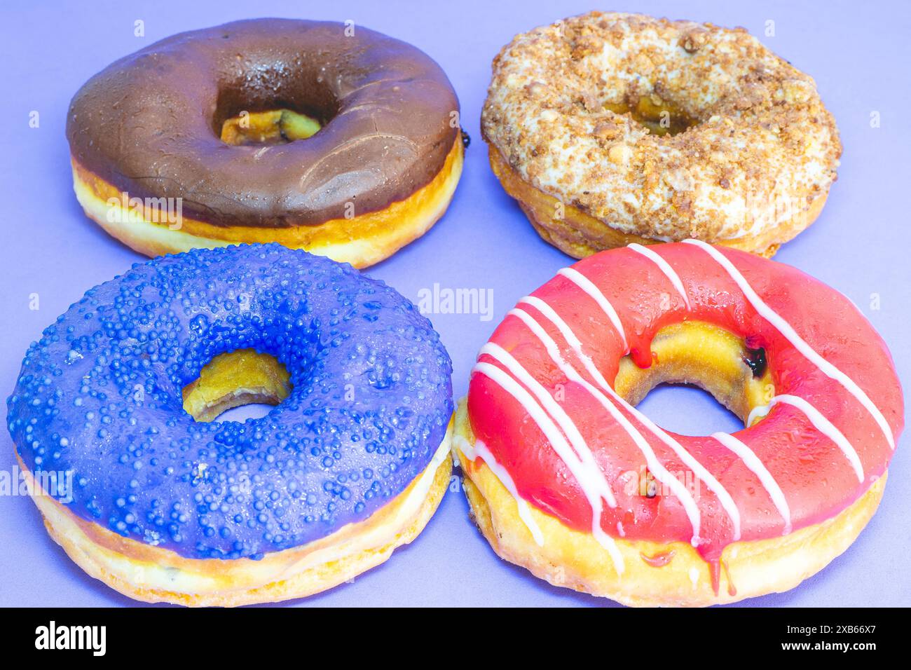 Four donuts with a different topping laying down on a blue background ...