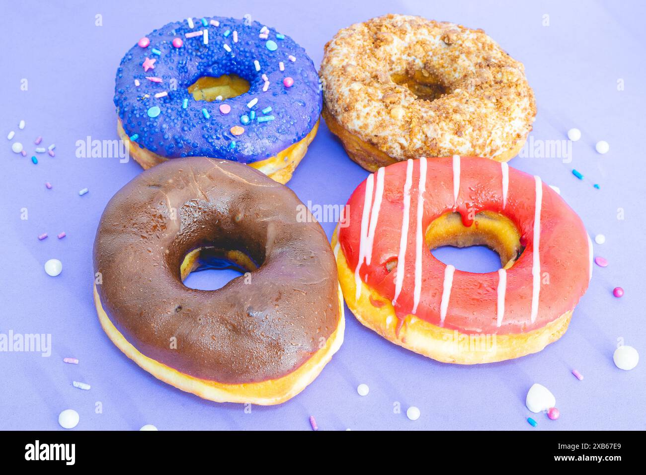 Four donuts with a different topping laying down on a blue background ...