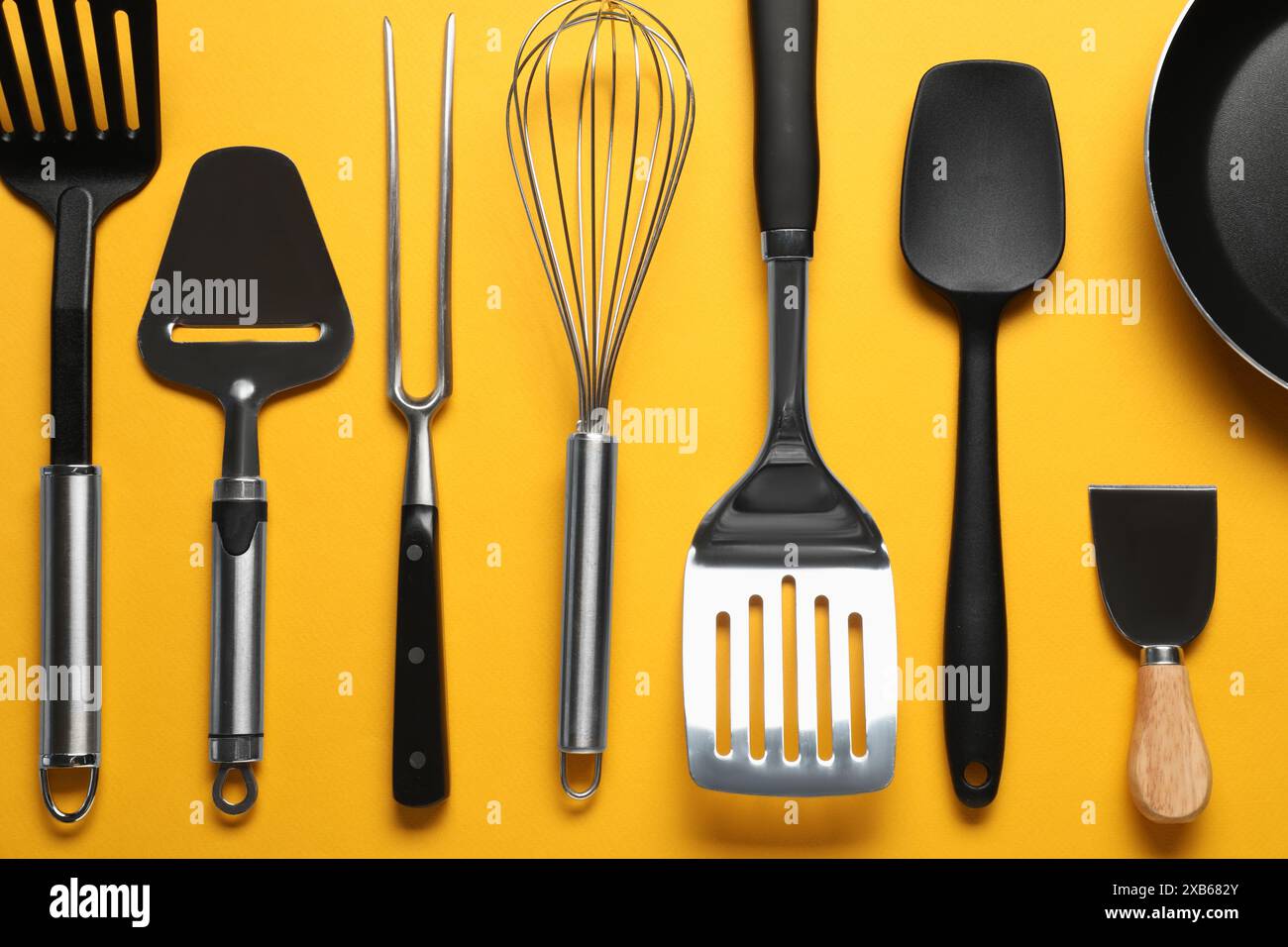 Different spatulas and other kitchen utensils on orange background ...