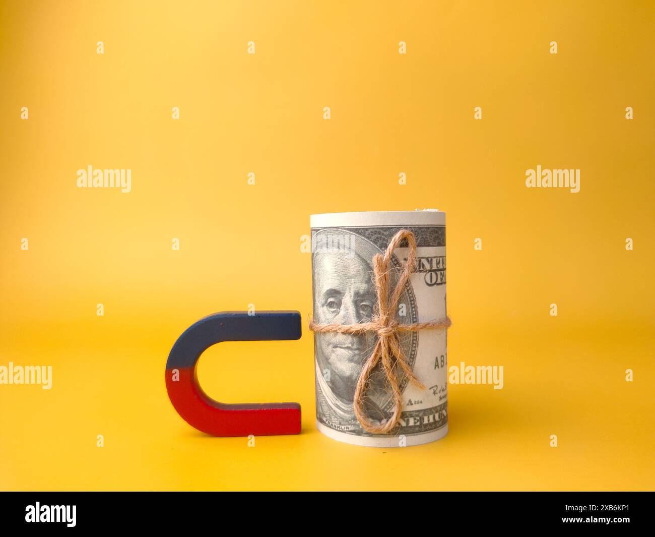 Magnet and banknotes on yellow background. The concept of attracts ...