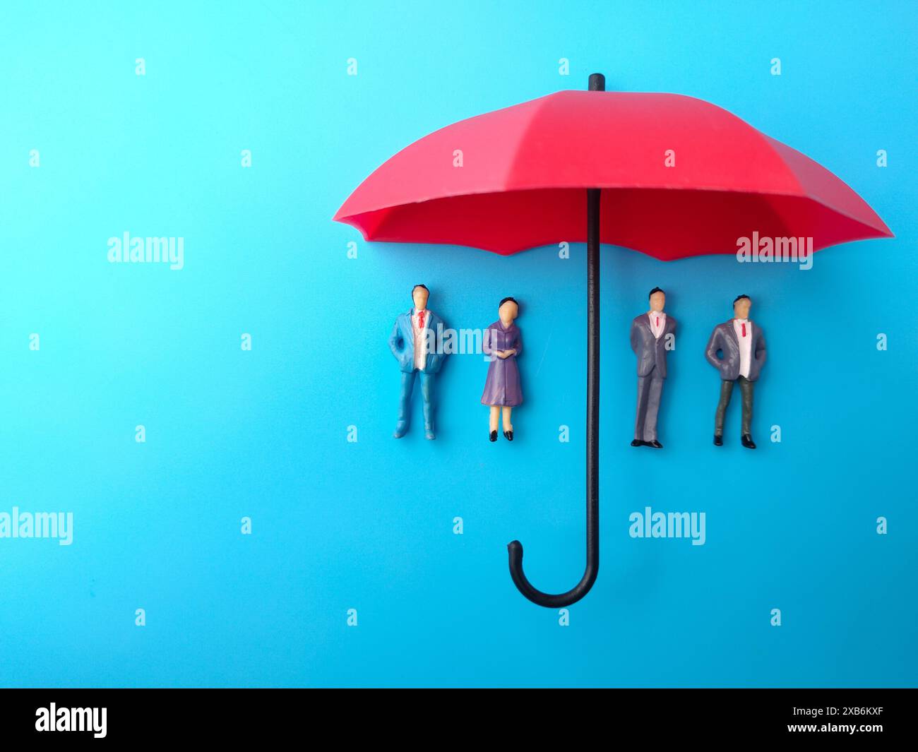 Miniature people cover by red umbrella on a blue background. Human or ...