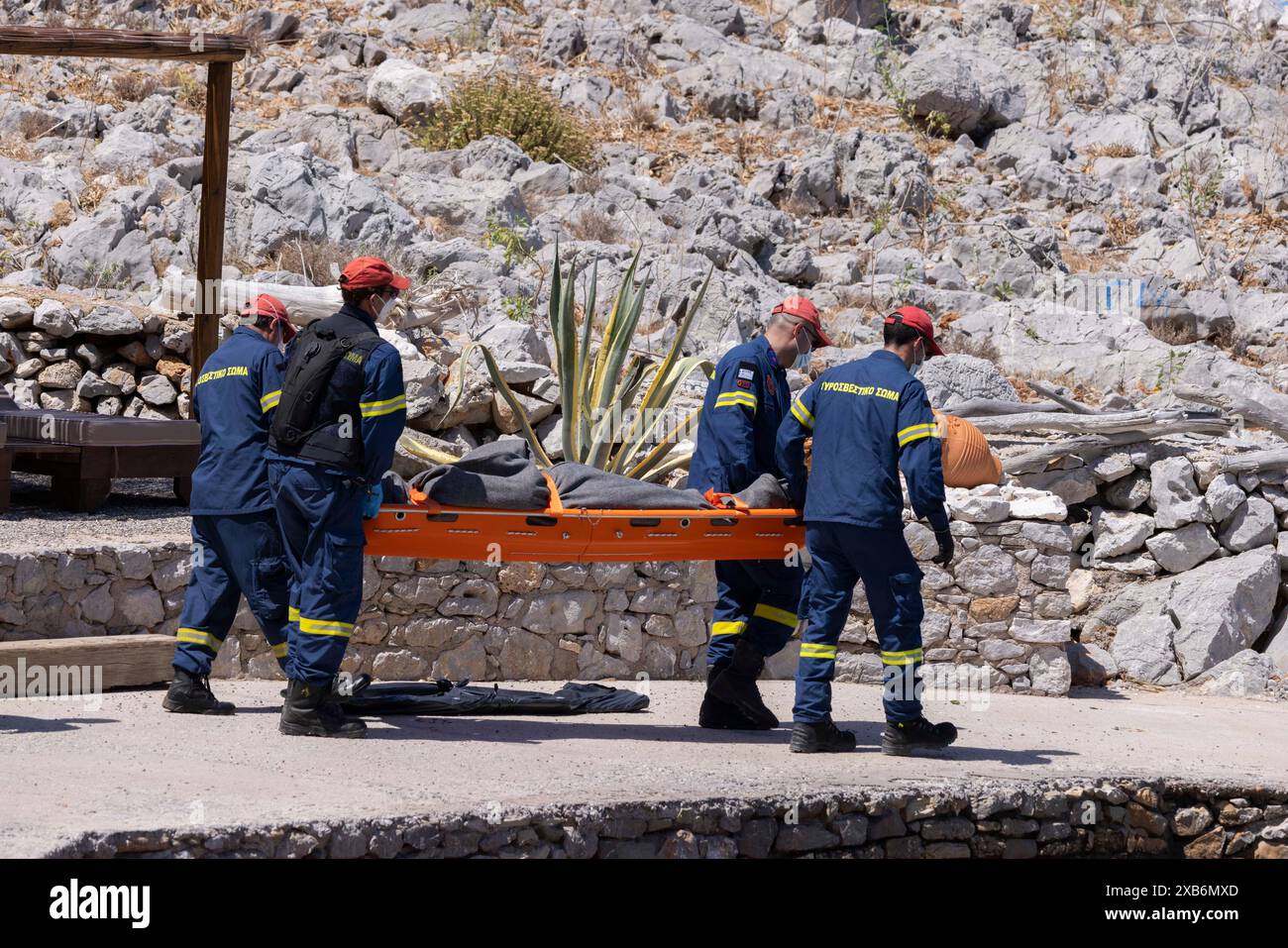Greek Fire Services officers carrying away on a stretcher the body of ...