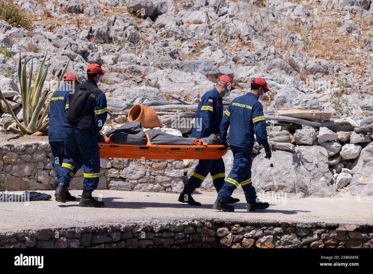 Greek Fire Services officers carrying away on a stretcher the body of ...