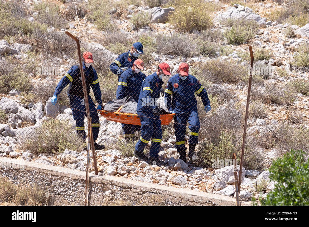Greek Fire Services officers carrying away on a stretcher the body of ...