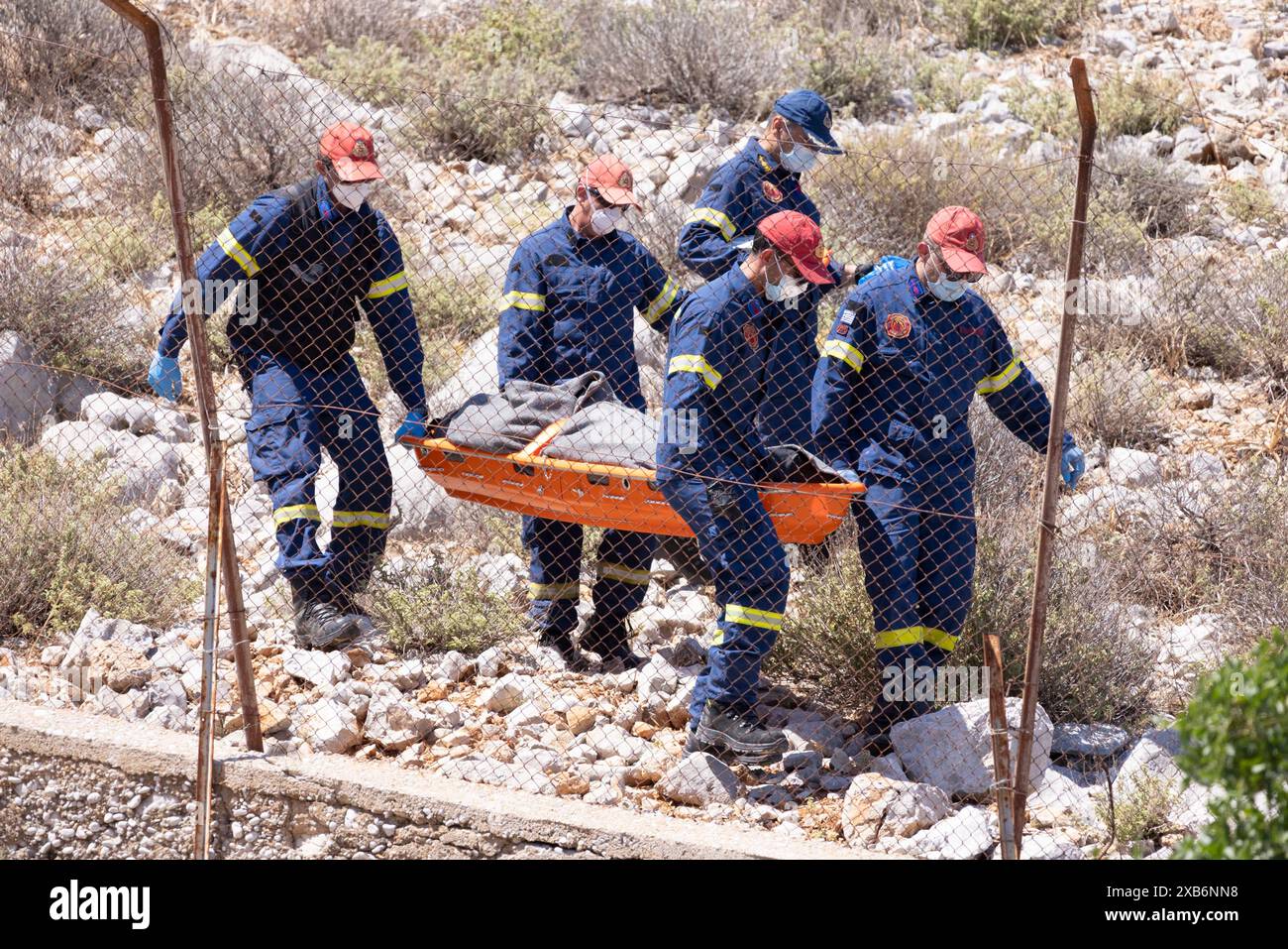 Greek Fire Services officers carrying away on a stretcher the body of ...