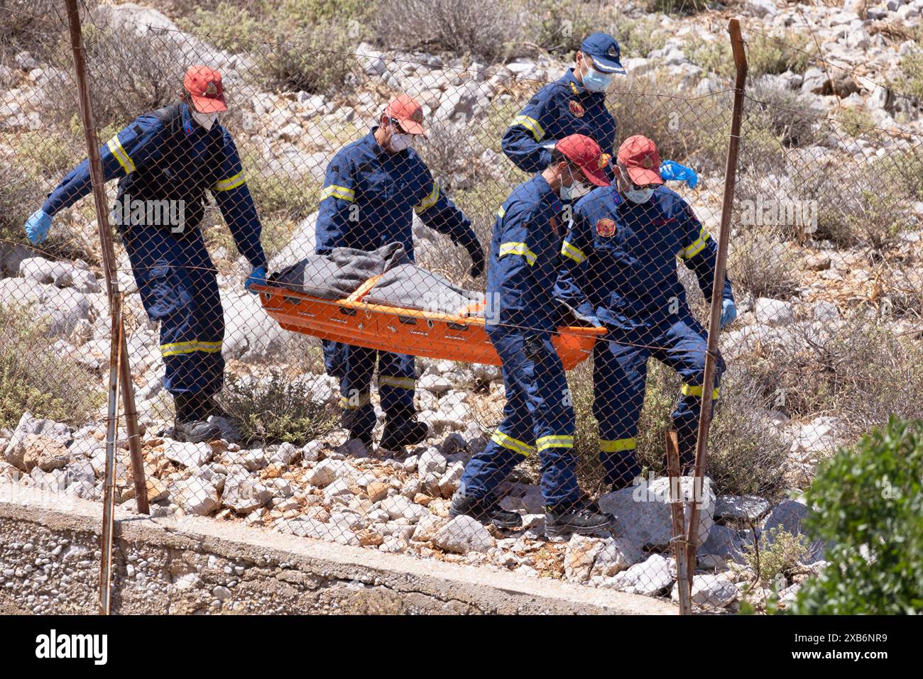 Greek Fire Services officers carrying away on a stretcher the body of ...