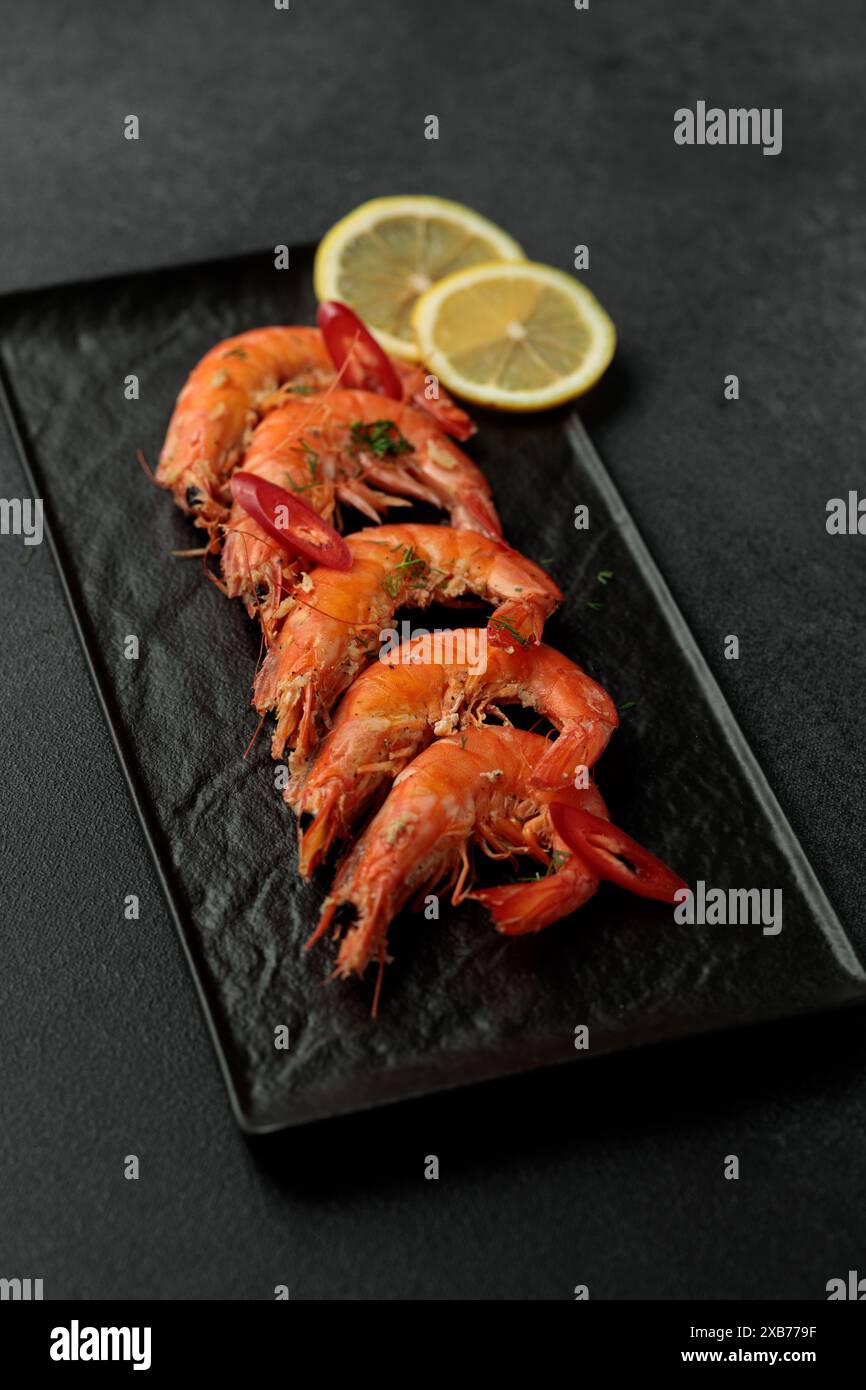 Large cooked king prawns on a black background. Lemon slices Stock ...