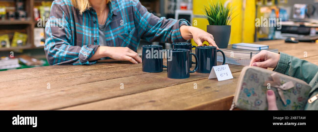 Banner of unrecognizable woman employee showing blue mugs to customer ...