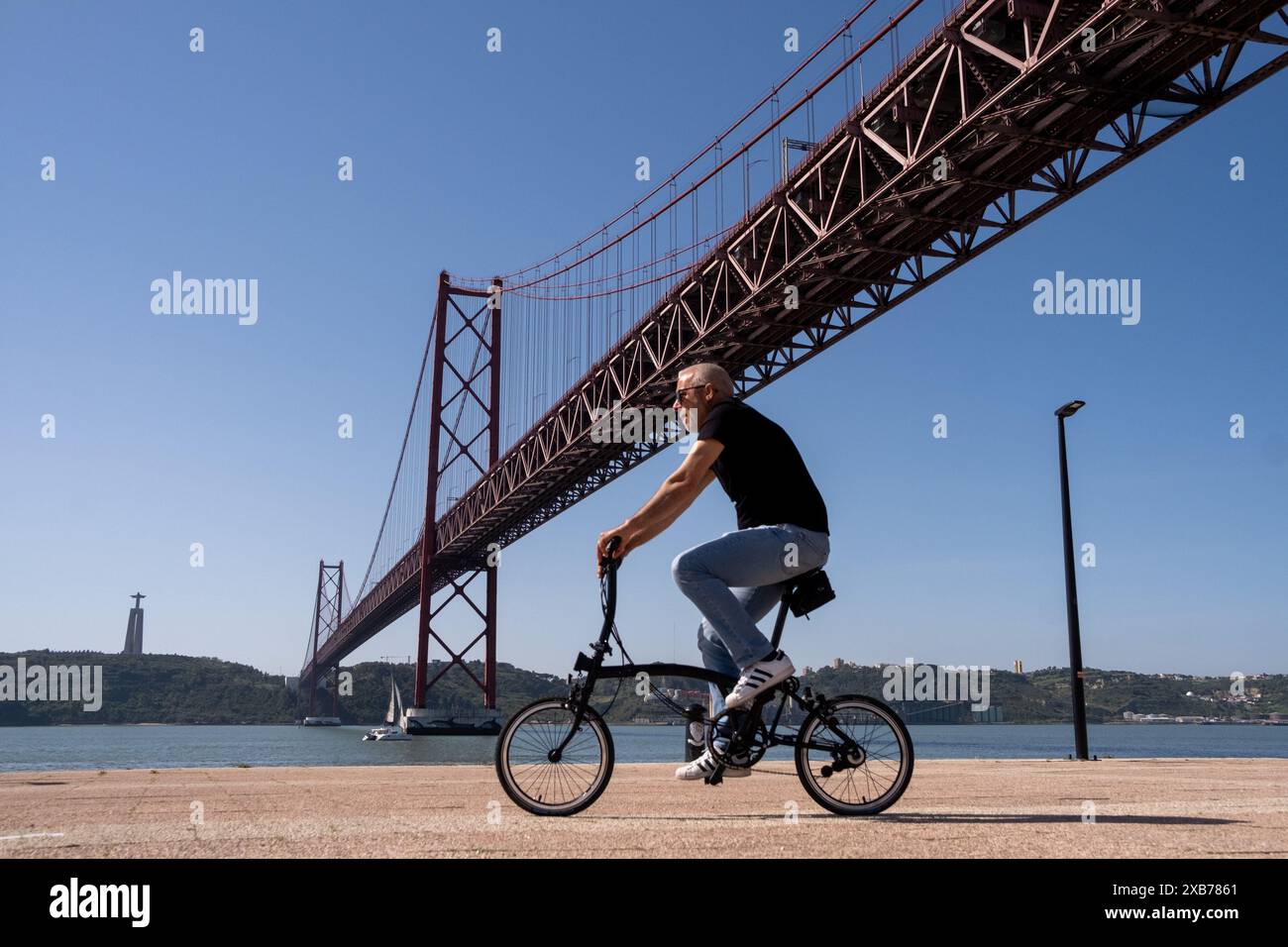 A cyclist with the 25 April Bridge (in Portuguese Ponte 25 de Abril), a ...