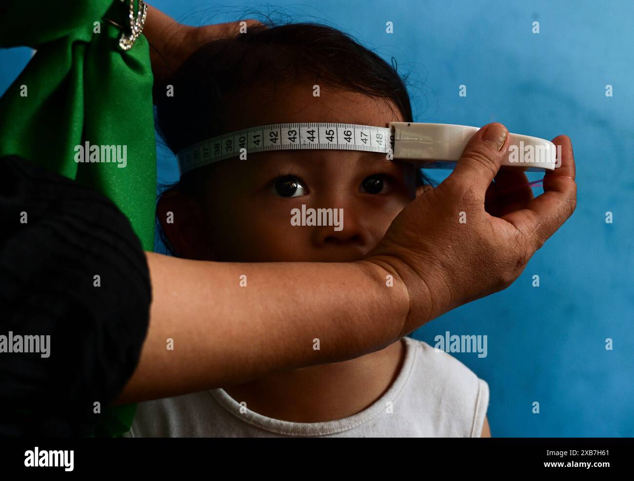 Jakarta, Indonesia. 11th June, 2024. A staff member measures a child's ...