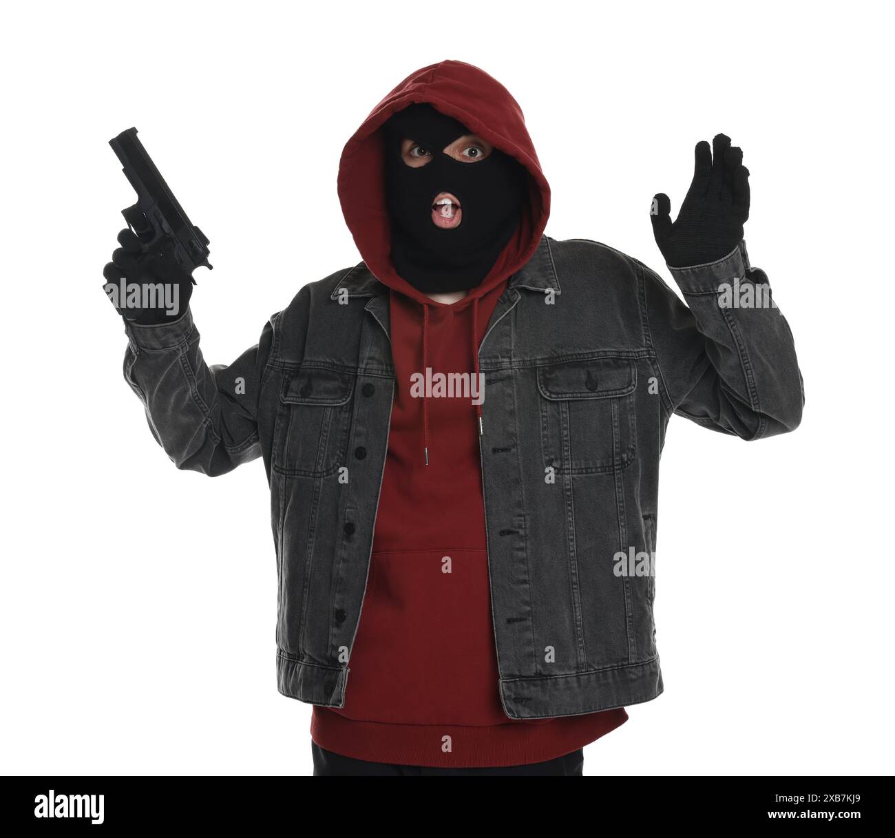 Emotional thief in balaclava raising hands with gun on white background ...