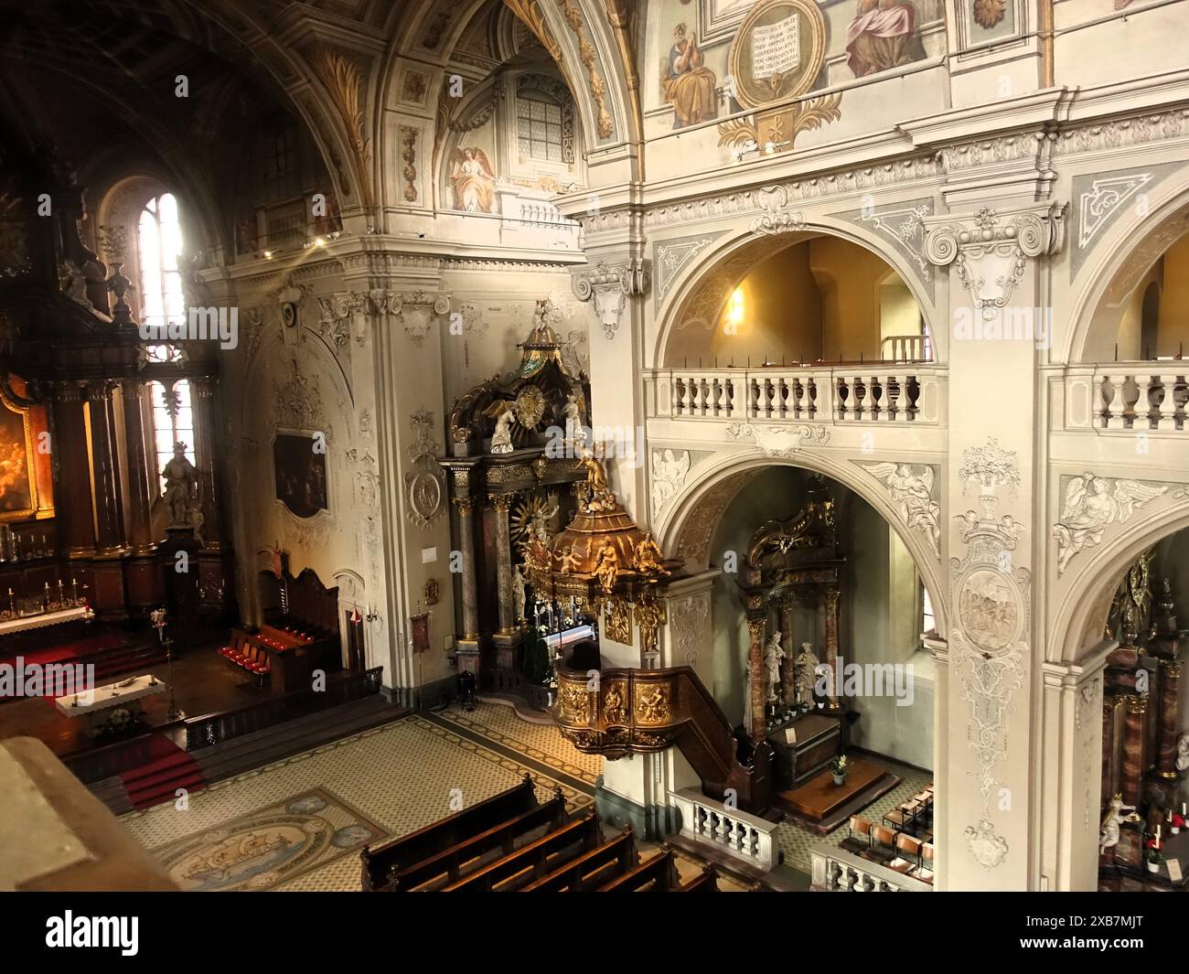 an Interior of a lavishly decorated church with rows of pews and stairs ...