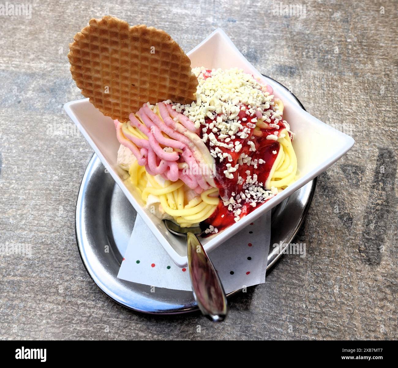 An Ice cream sundae topped with sprinkles and strawberry swirl with a ...