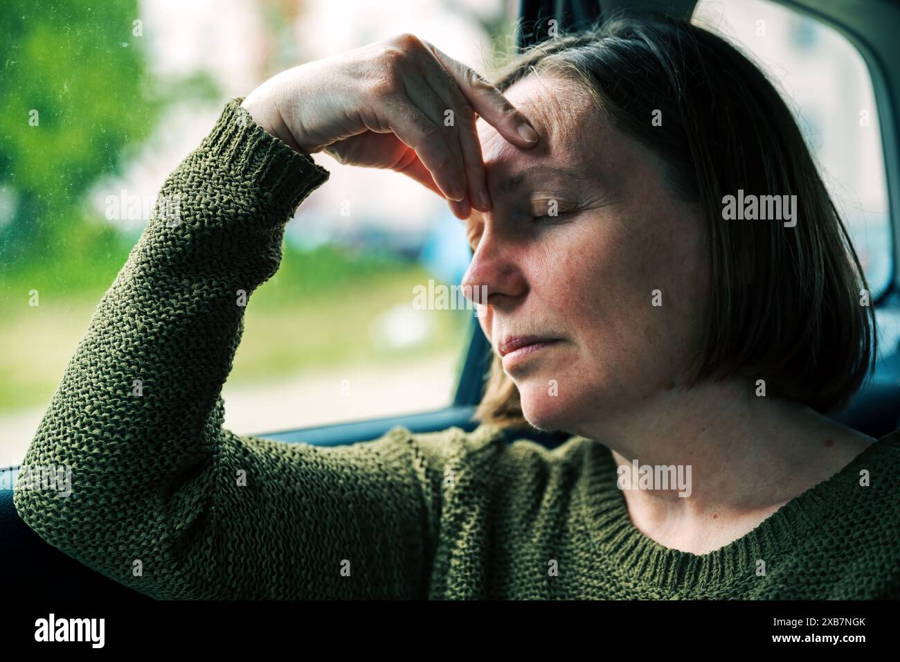 Motion sickness and car ride headache concept, woman at the back seat ...