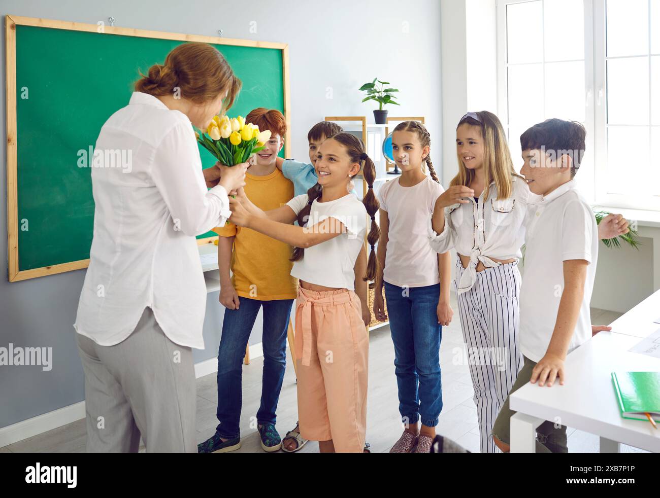 Children students giving flowers to their teacher at elementary school ...
