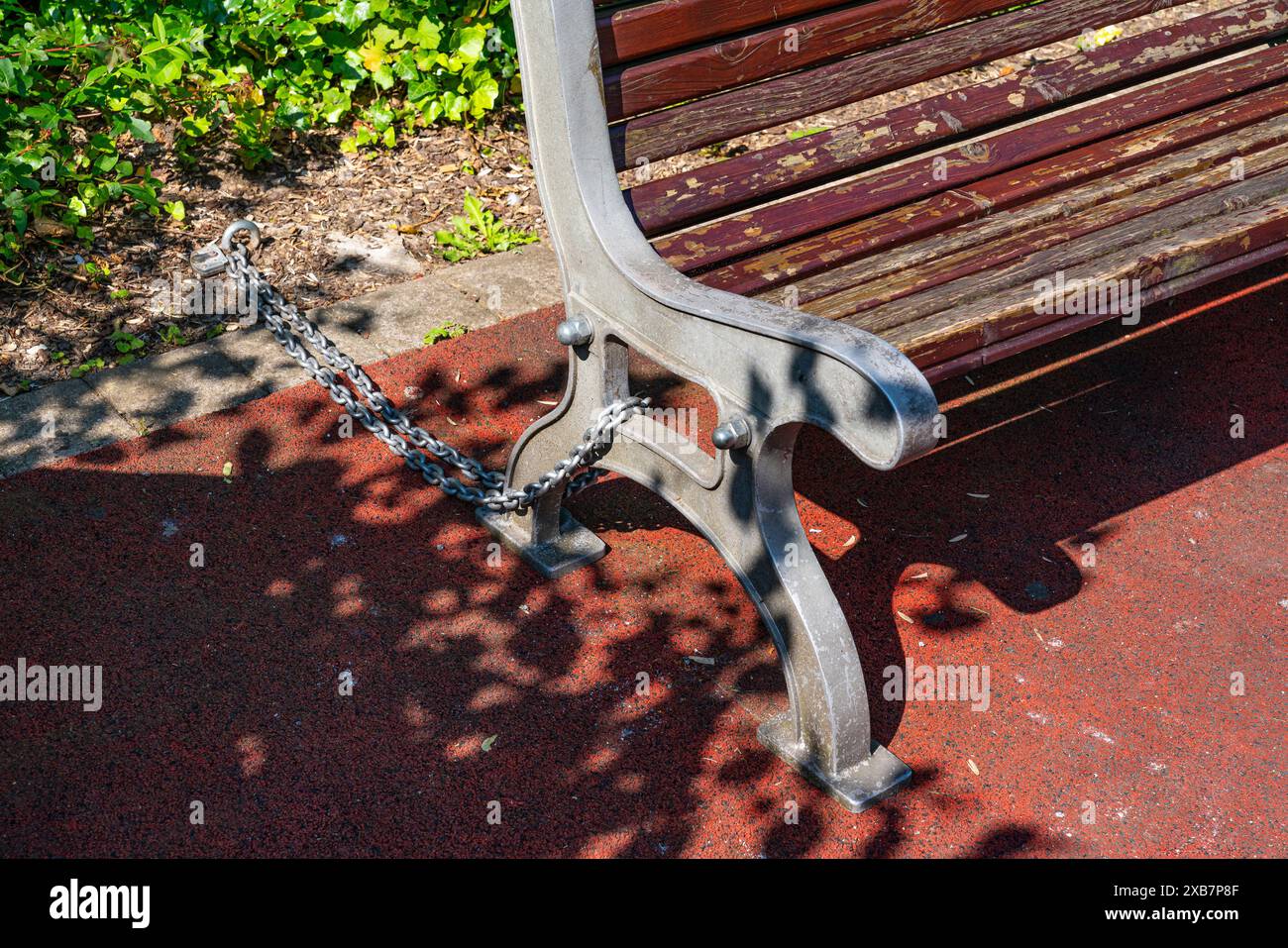 Wooden bench in the park chained with a metal chain to a pin driven ...