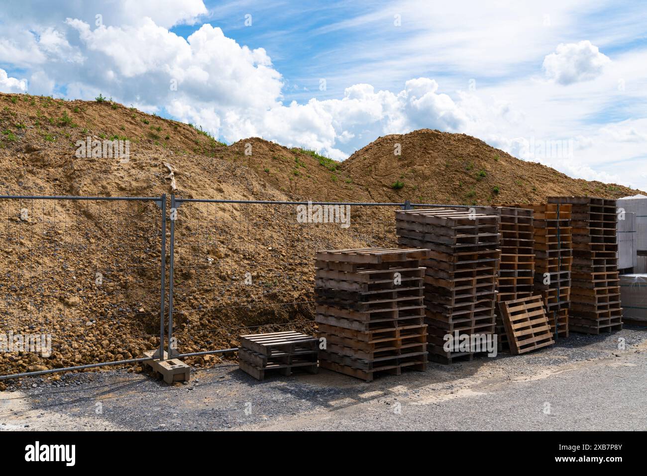 Wooden pallets stacked in front of a metal fence against the backdrop ...