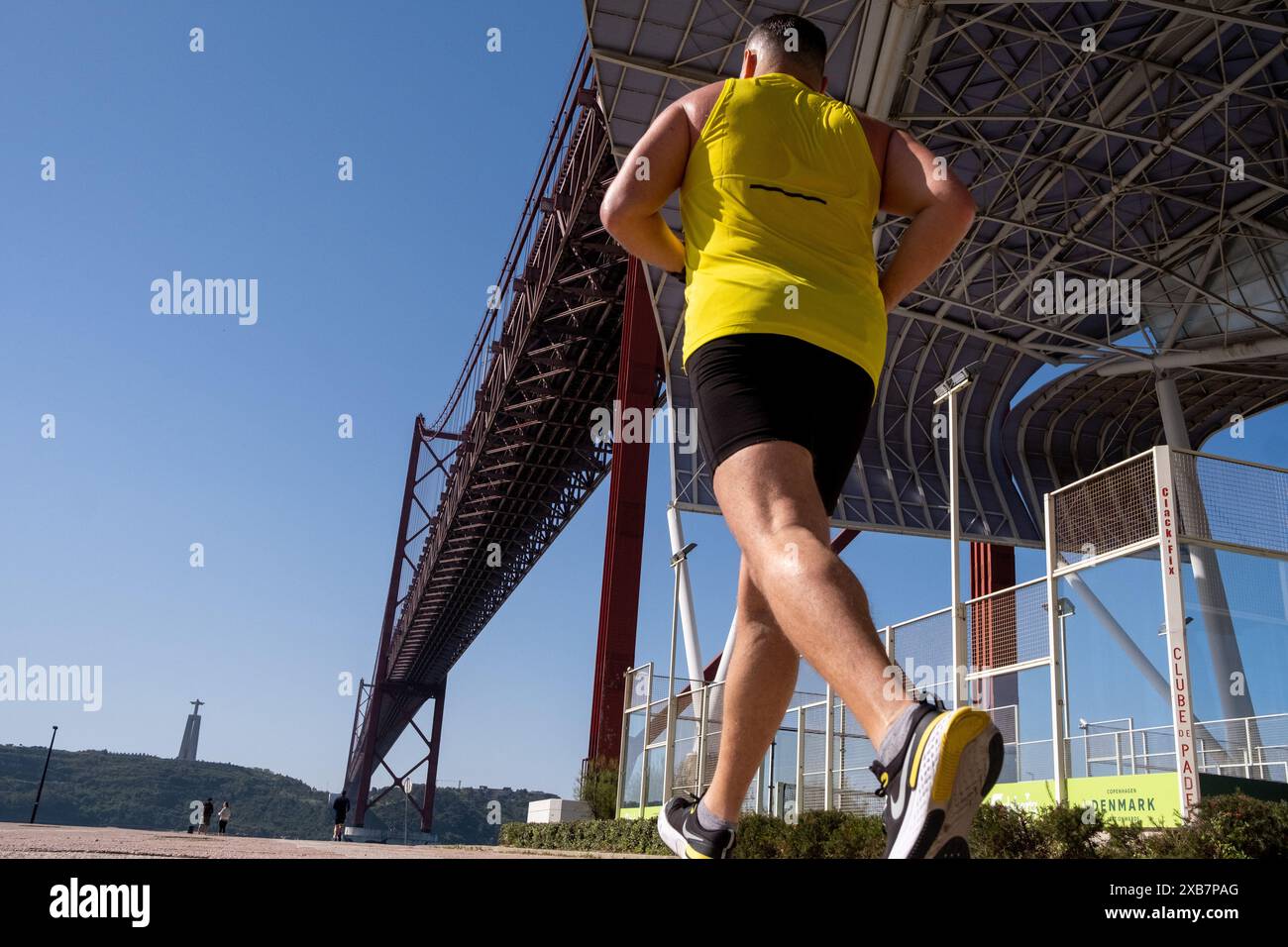 A runner with the 25 April Bridge (in Portuguese Ponte 25 de Abril), a ...