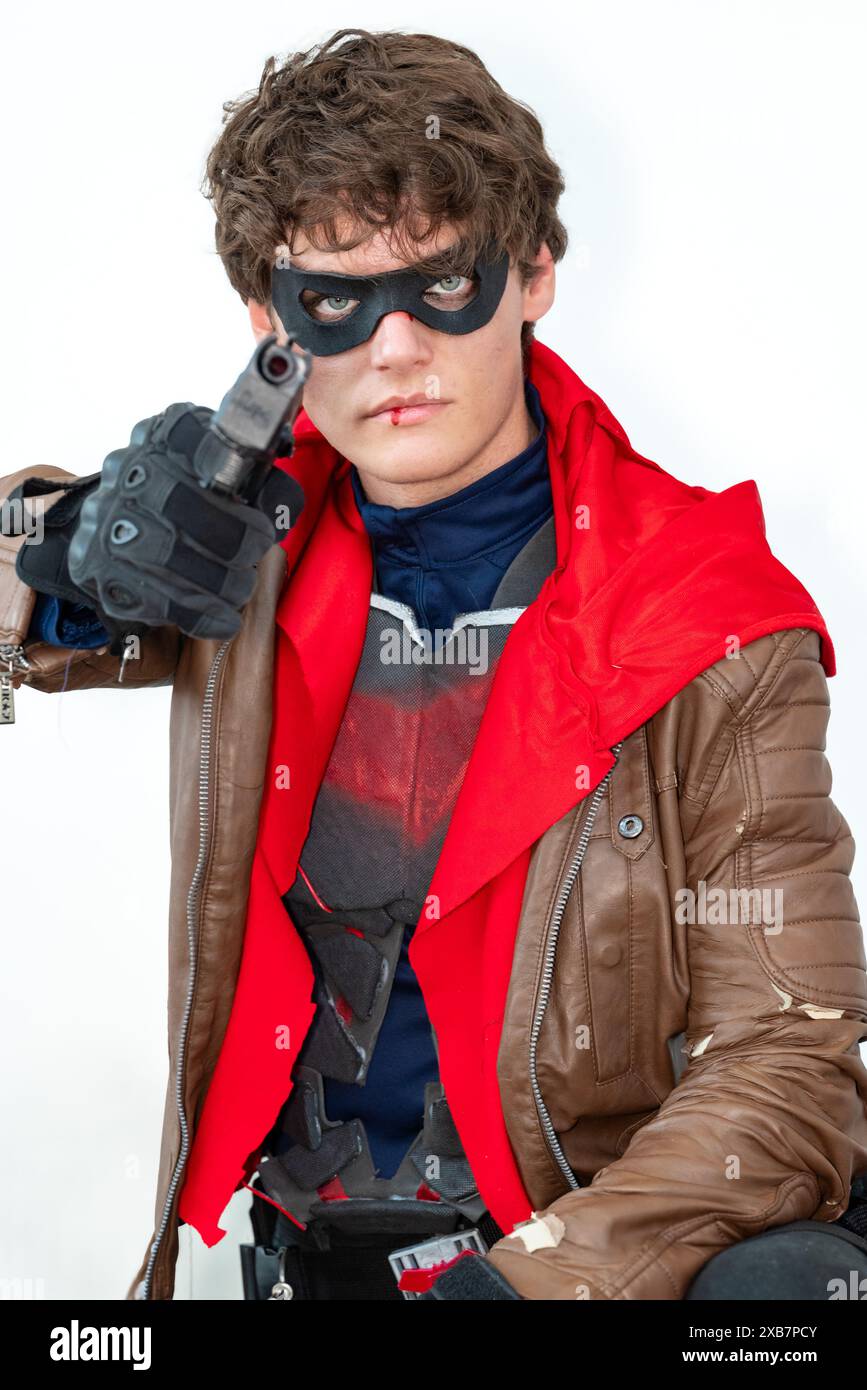 A young boy in costume and glasses with a leather coat, holding guns ...