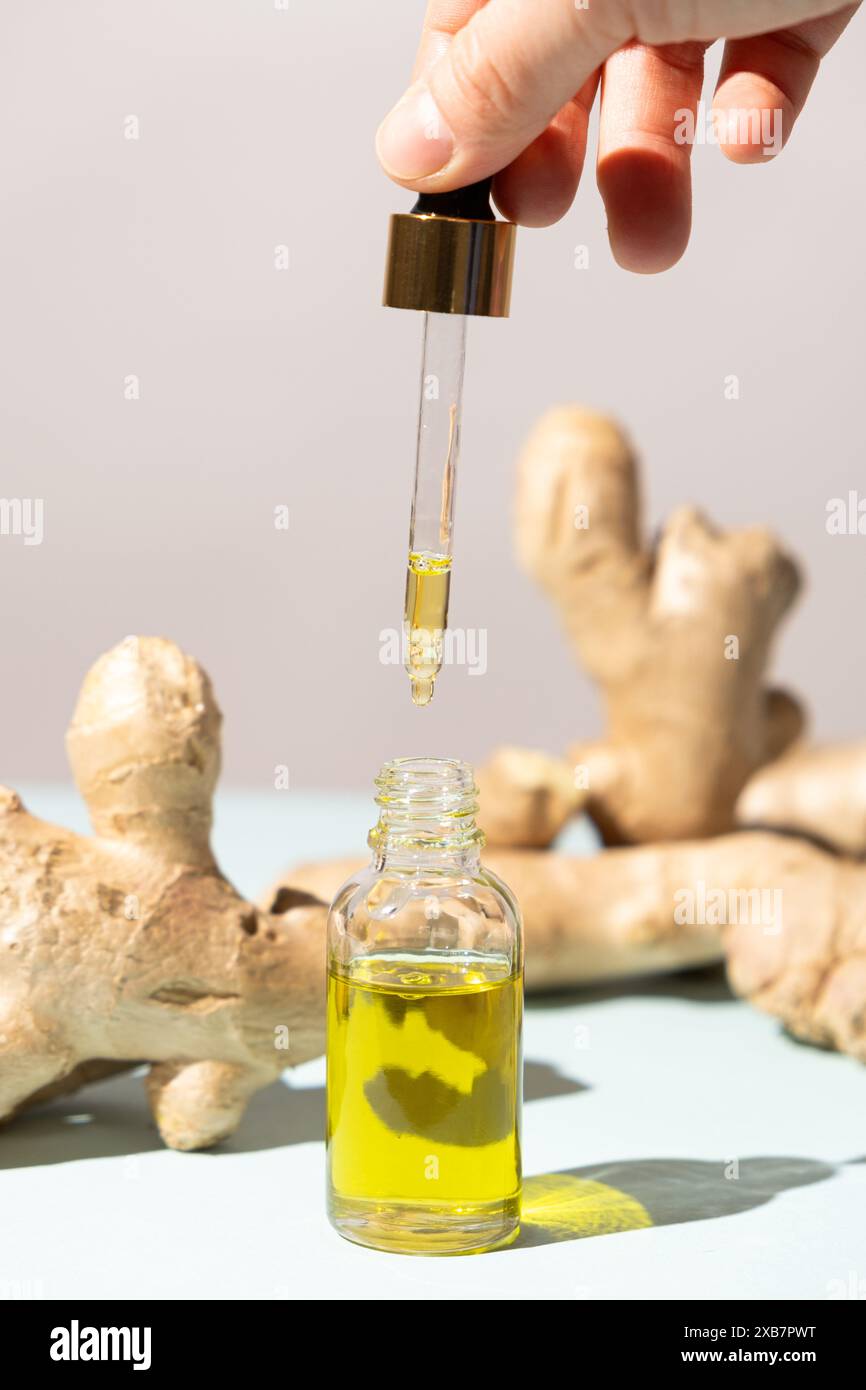Natural ginger essential oil dripping from pipette into glass bottle Stock Photo - Alamy