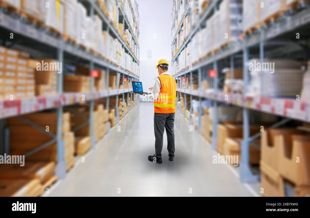 Asian worker or engineer in warehouse with stack of cardboard boxes ...
