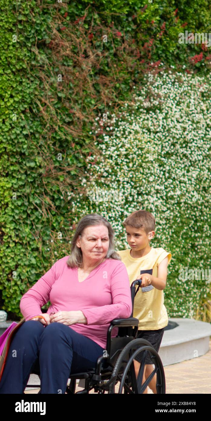 Grandson carrying his grandmother in a wheelchair with a background of ...