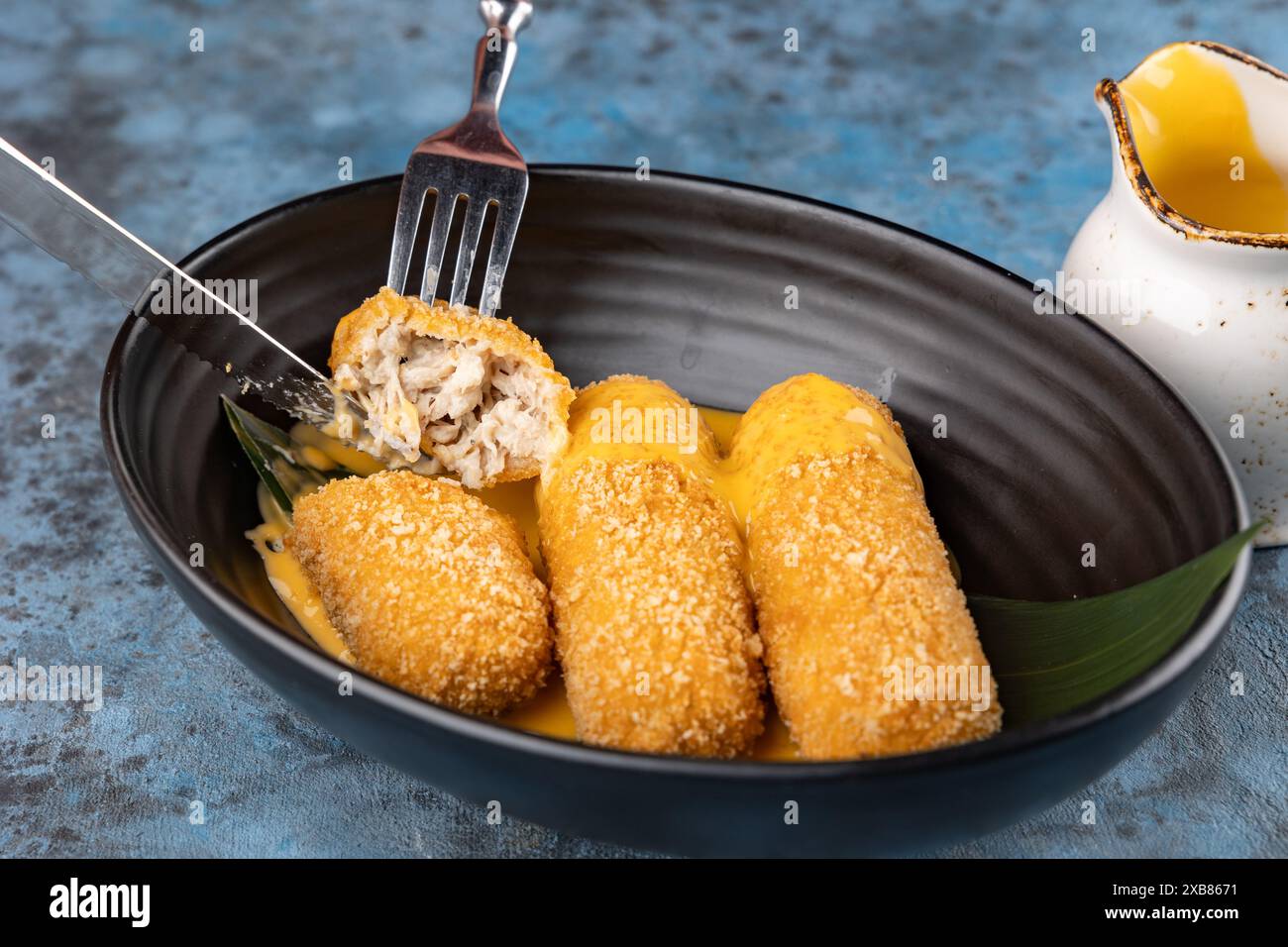 Pile of breaded chicken stick snacks on the black plate over the blue ...