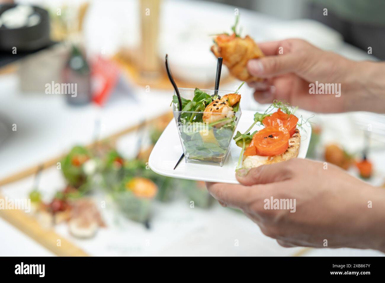 catering. Hands putting salad with shrimp and bruschetta with salmon on ...