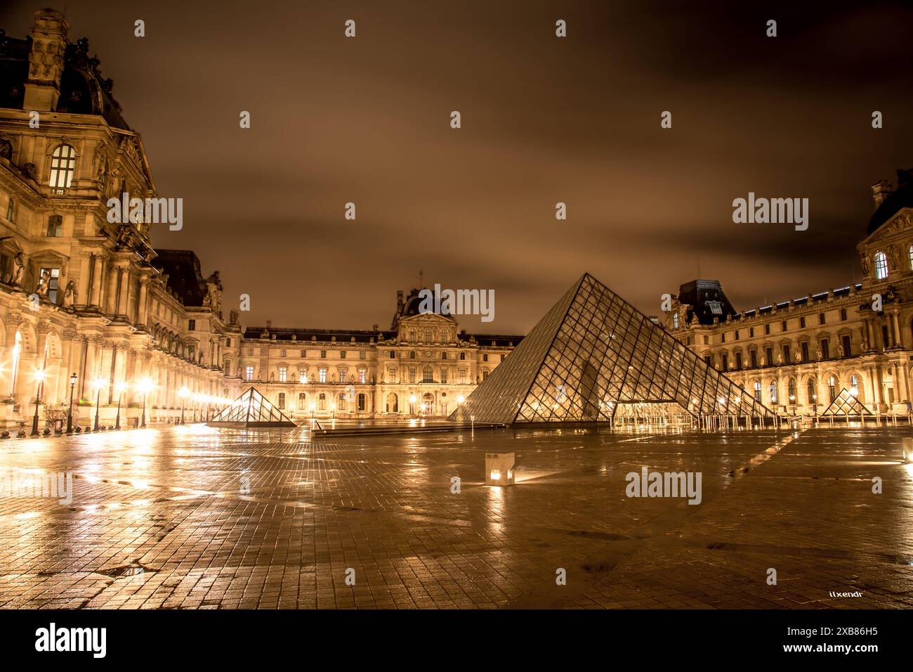 Illuminated pyramid in courtyard with buildings in the background at ...