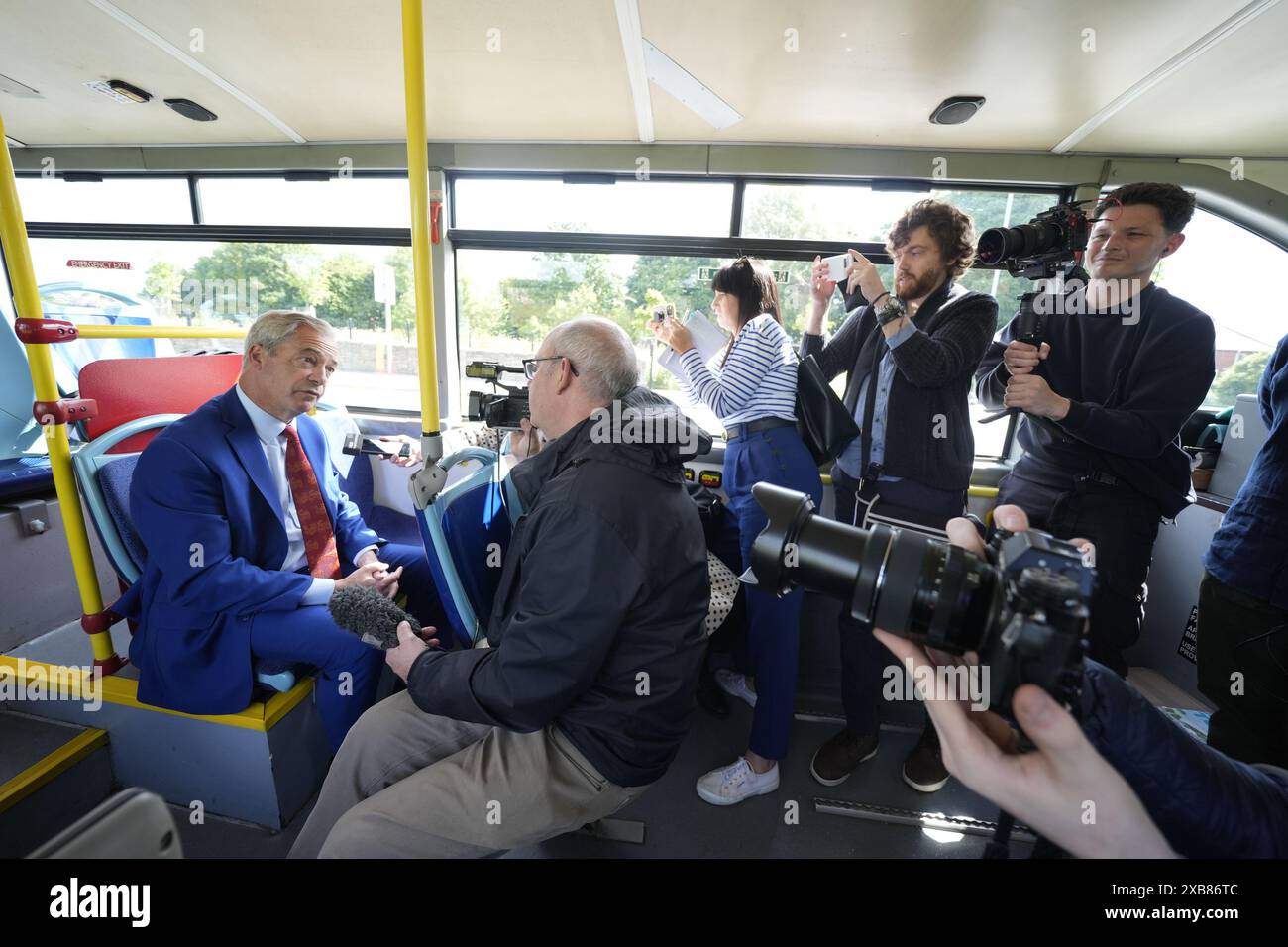 Reform UK leader Nigel Farage (left) speaks to the media on board the ...