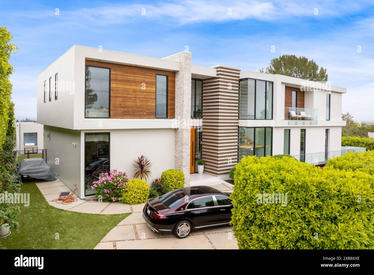 A Contemporary two-story home in sunny setting with car parked out ...