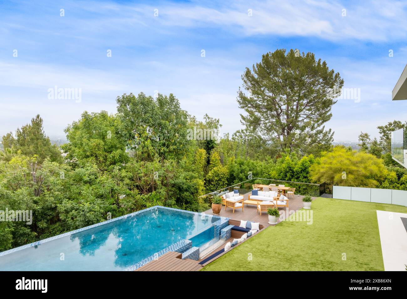 A spacious pool set amidst lush greenery and a wooden deck Stock Photo ...