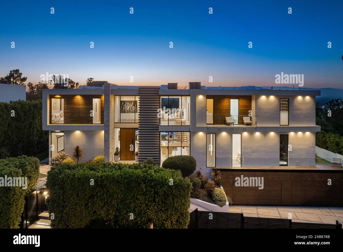 A Spacious white concrete house surrounded by lush green shrubbery ...