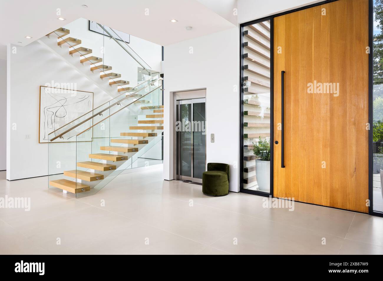 A room with stairs, a large door and an elevator inside a luxurious ...