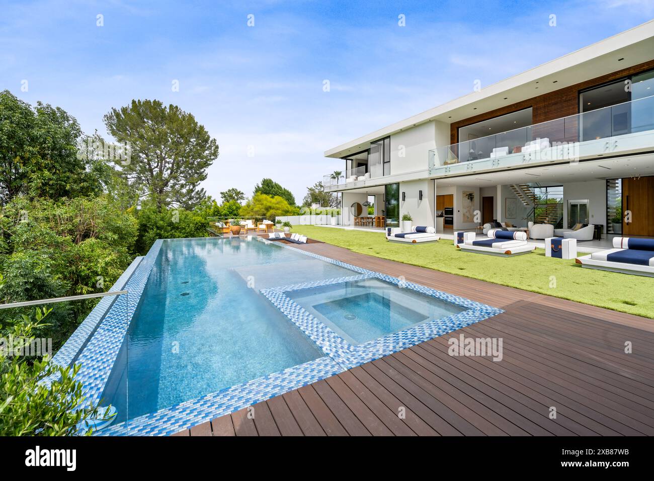 An unoccupied pool surrounded by trees and a deck underneath Stock ...