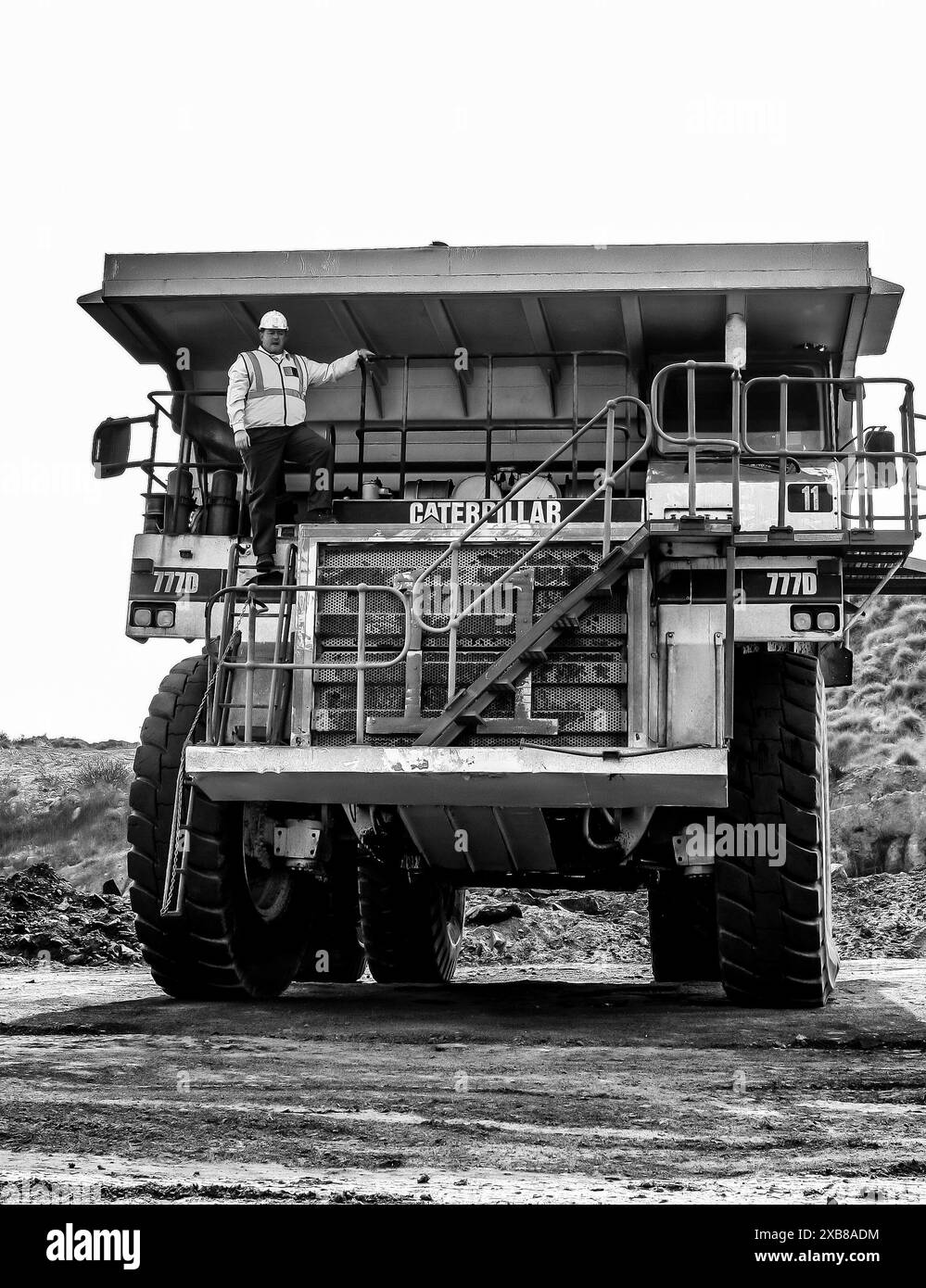 Man sits on a big dump truck in the desert Stock Photo - Alamy