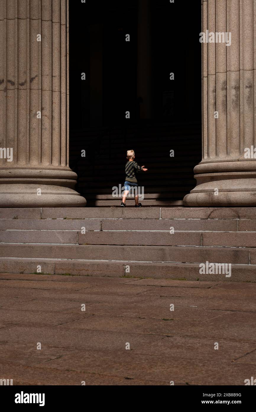 A young boy running down steps near a grand stone structure Stock Photo ...