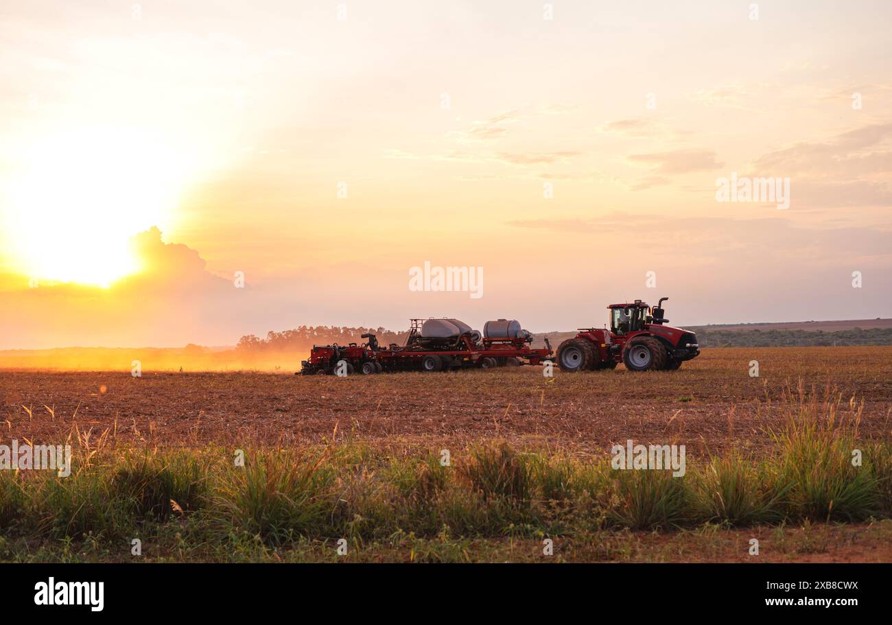 A farmer operating a tractor in the field during sunset Stock Photo - Alamy