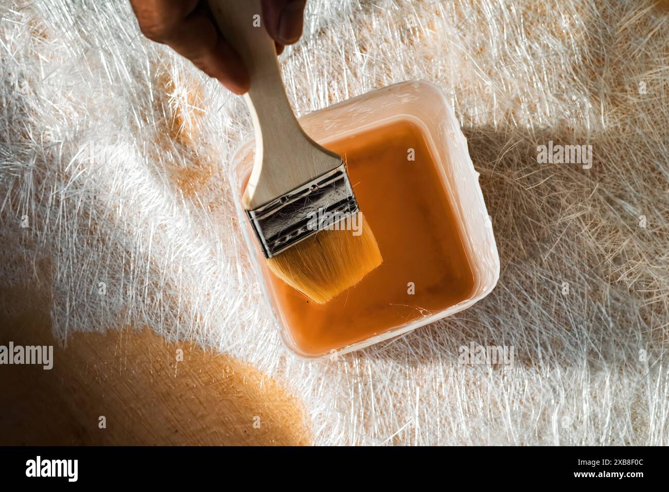 Paint brush inside the fiberglass solution in a container on top of the ...