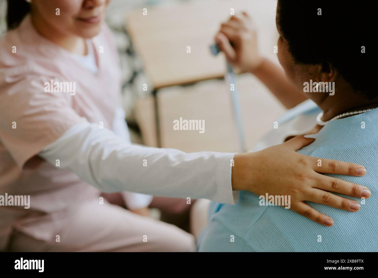 Nurse shoulder tapping mature African American female patient gently ...