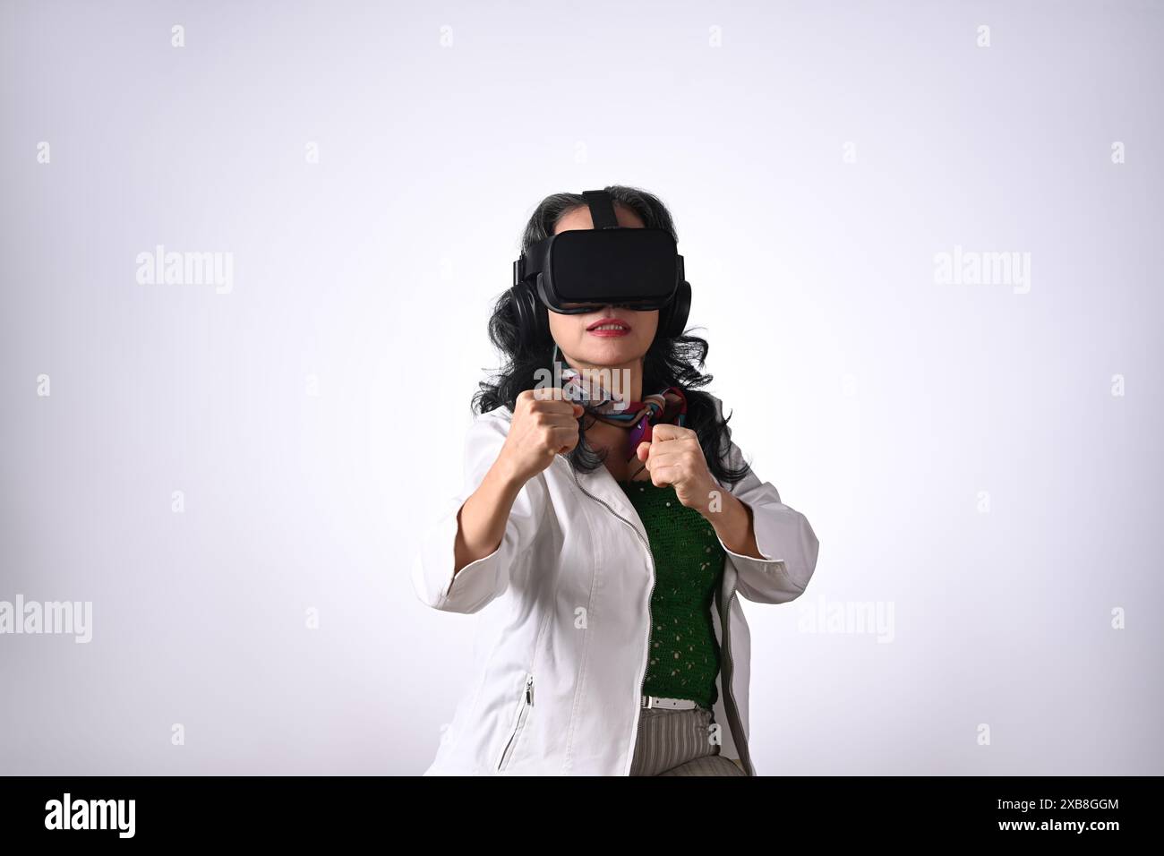 Senior woman in boxing stance, playing action simulator game in VR ...