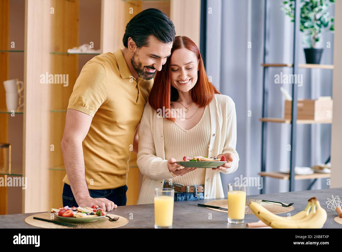 A stylish couple enjoys a snack in their modern kitchen, sharing a ...
