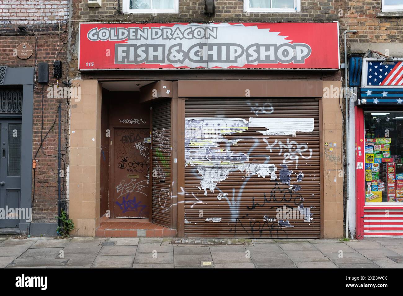 A closed chip shop in London with untidy, graffiti on window shutters ...