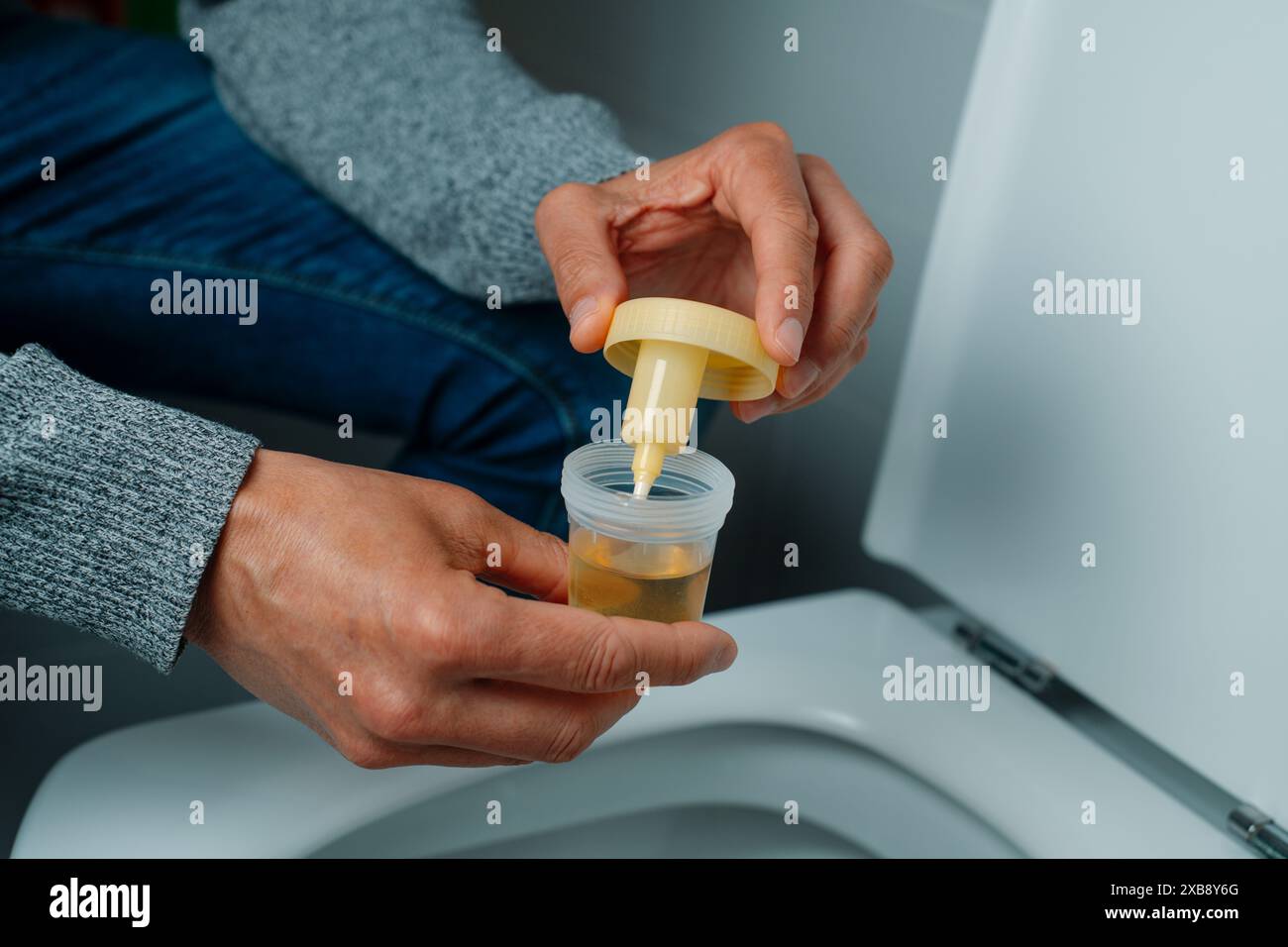closeup of a man collecting a urine sample in a sterile container, in ...
