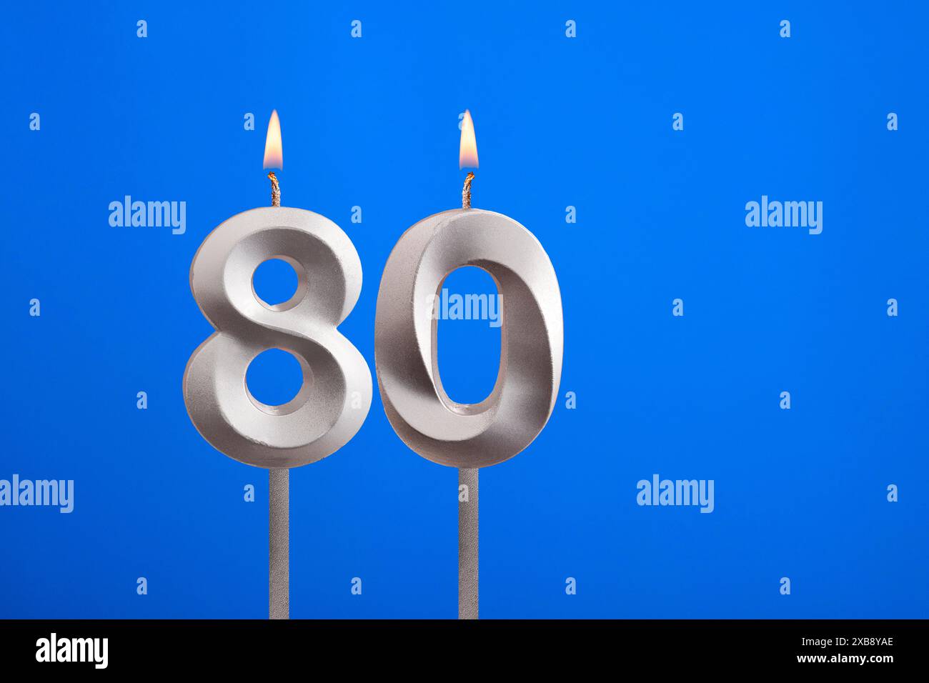 Birthday number 80 - Candle lit on blue background Stock Photo - Alamy
