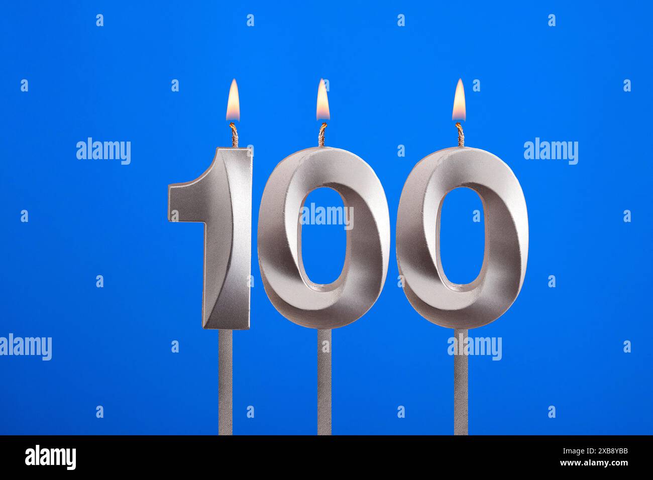 Birthday number 100 - Candle lit on blue background Stock Photo - Alamy